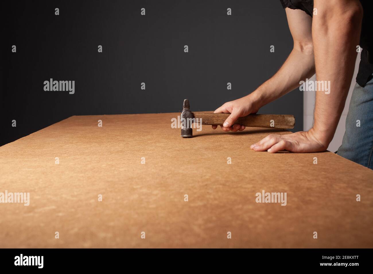 A man hammers nails into a cupboard. The back wall of the cupboard is ...
