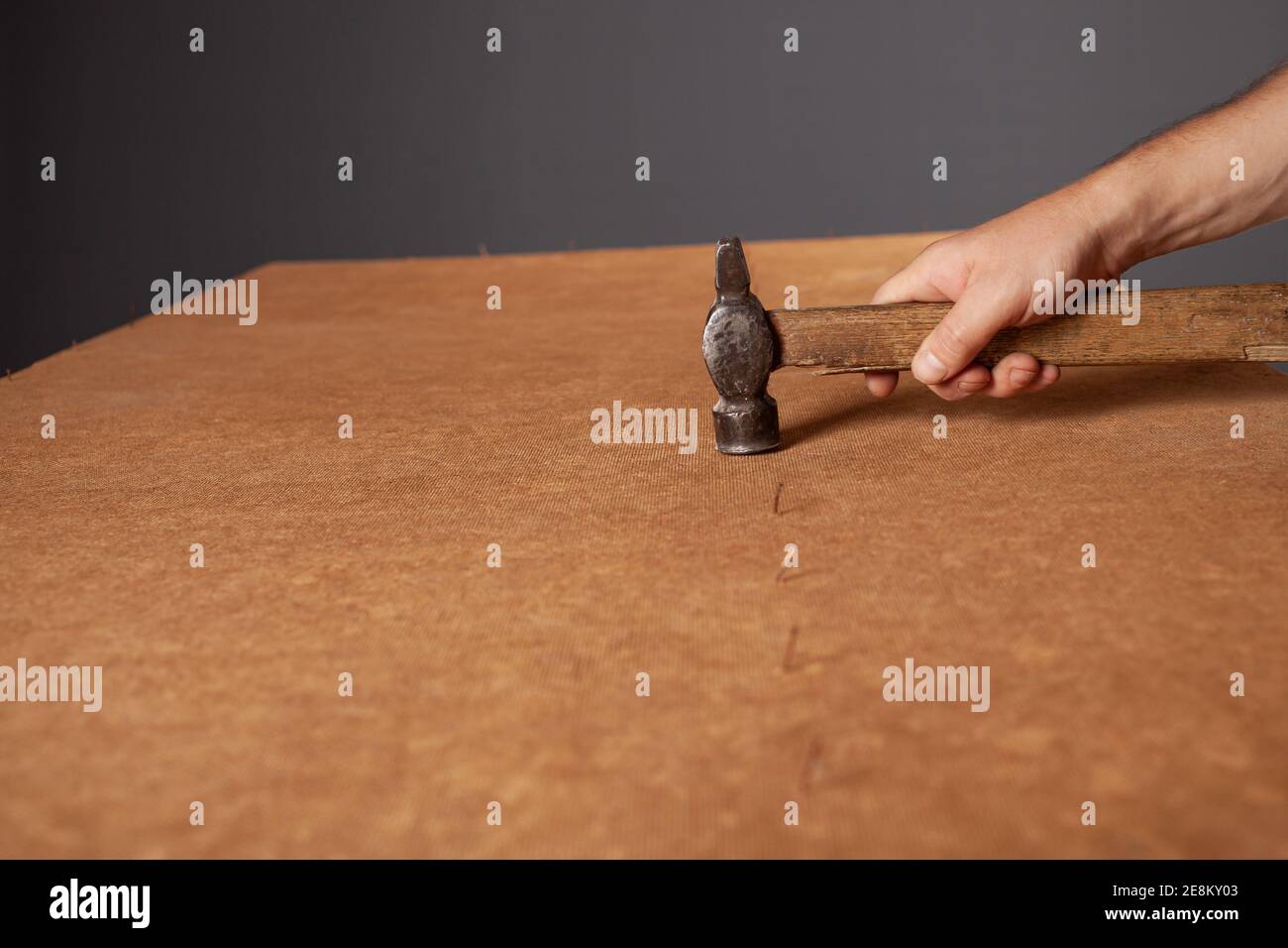A man hammers nails into a cupboard. The back wall of the cupboard is ...
