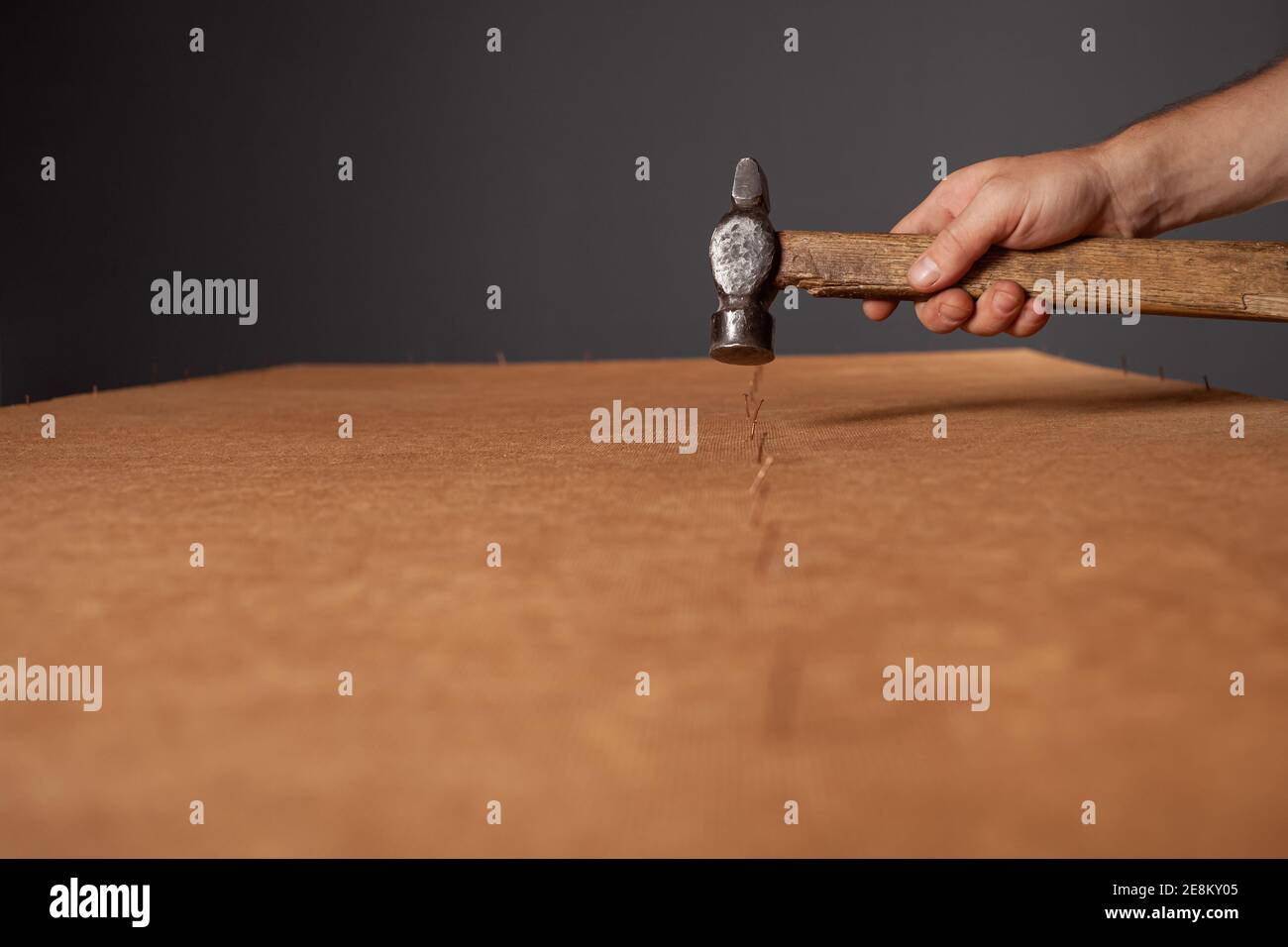 A man hammers nails into a cupboard. The back wall of the cupboard is ...