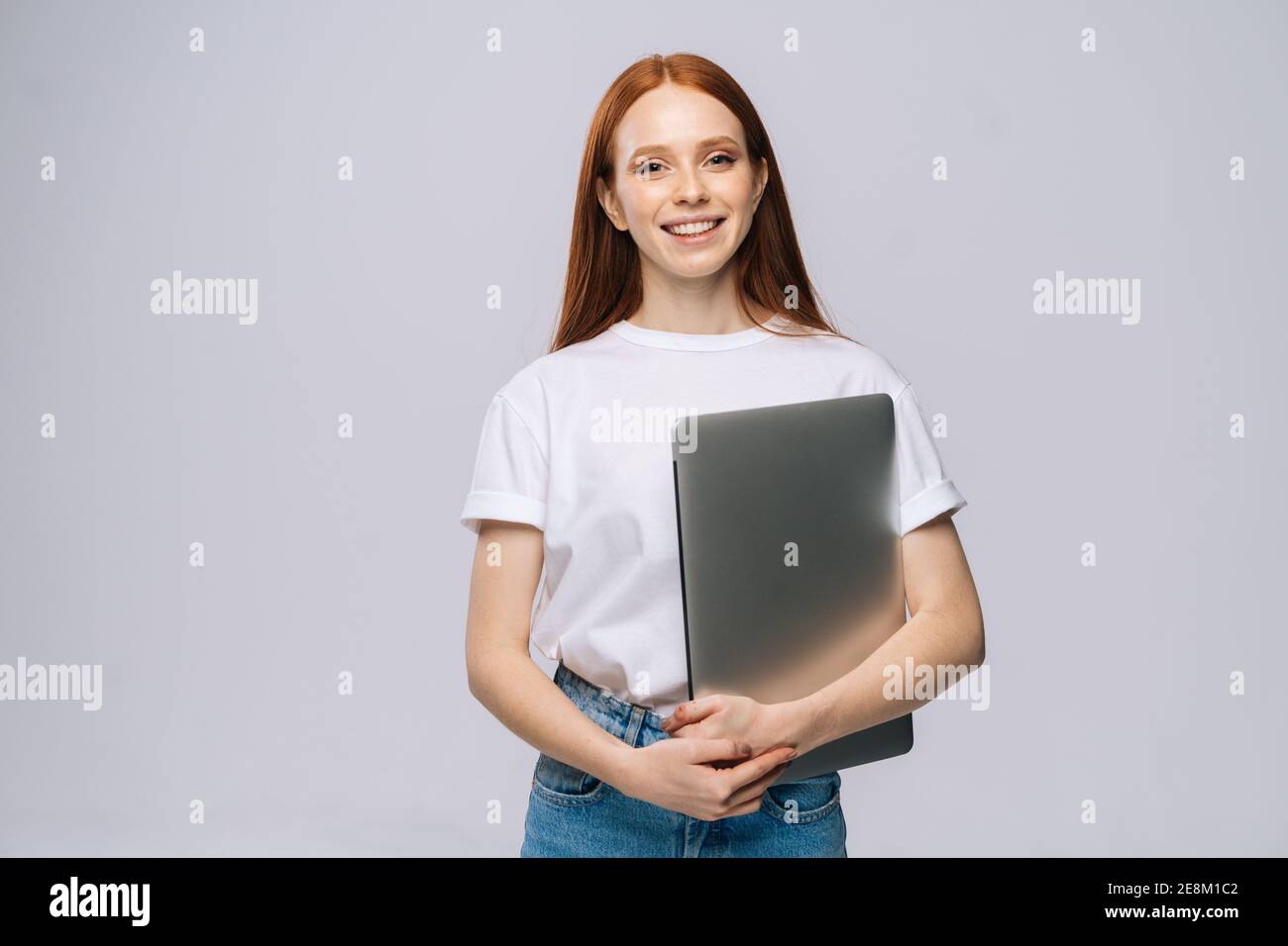 Charming young woman student holding laptop computer and looking at ...
