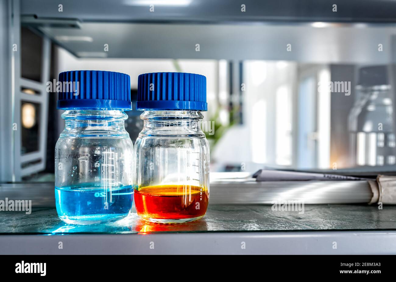 Closeup of laboratory glassware filled with blue and orange liquids ...