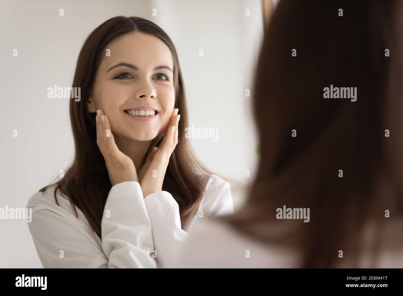 Happy young woman look in mirror touch healthy face Stock Photo - Alamy