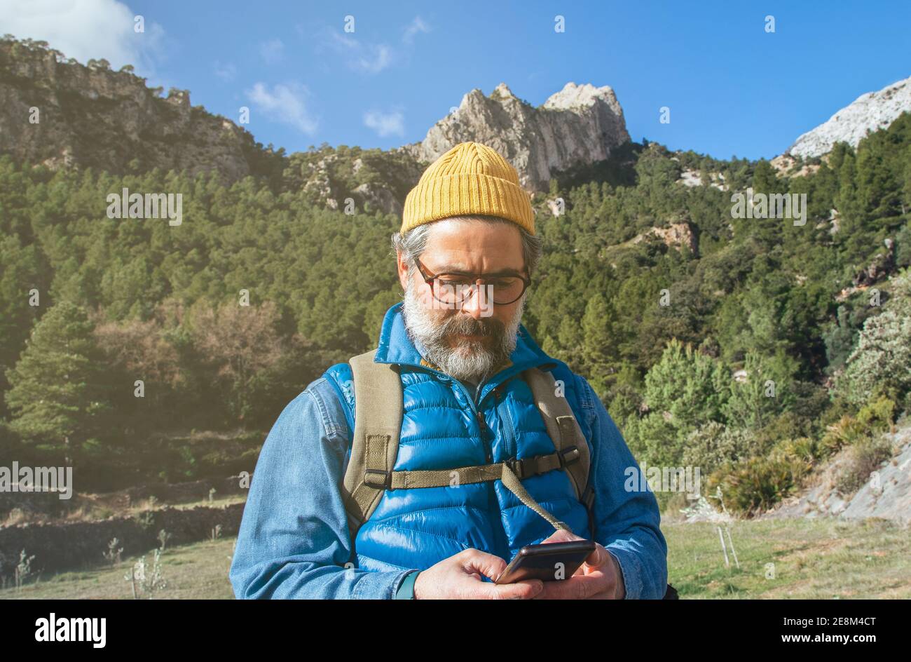 Portrait of a bearded explorer man walking through the mountains, using ...