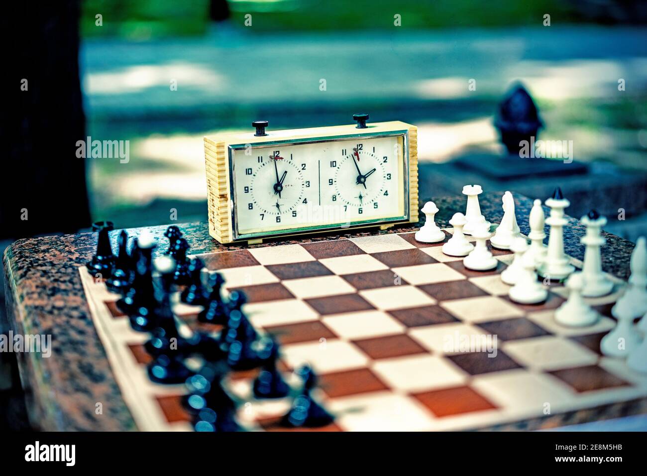 Chess board with pieces and clock on wooden desk In connection with the ...