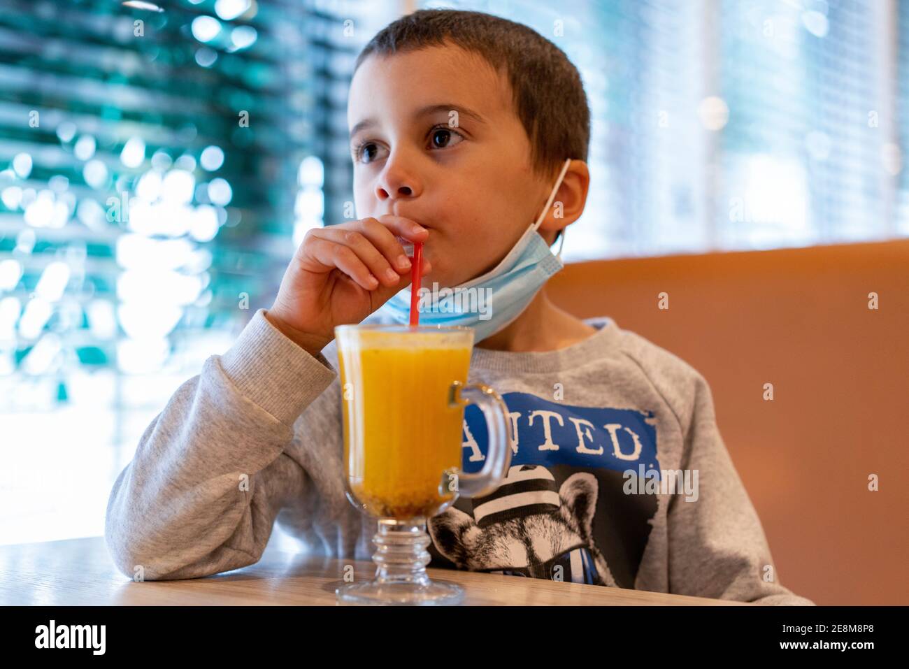 Little boy in a medical mask in a cafe eats a cake. A child wearing a ...