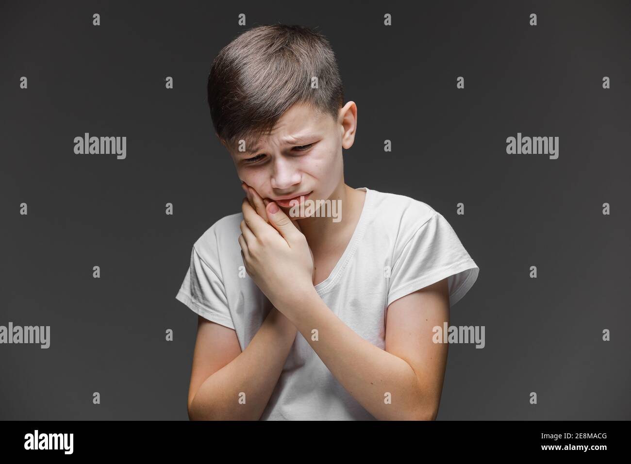 Child toothache. holding his cheek, dental pain. Closeup portrait boy ...