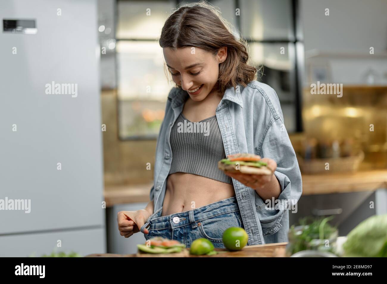 Happy slim woman showing her weight loss Stock Photo - Alamy