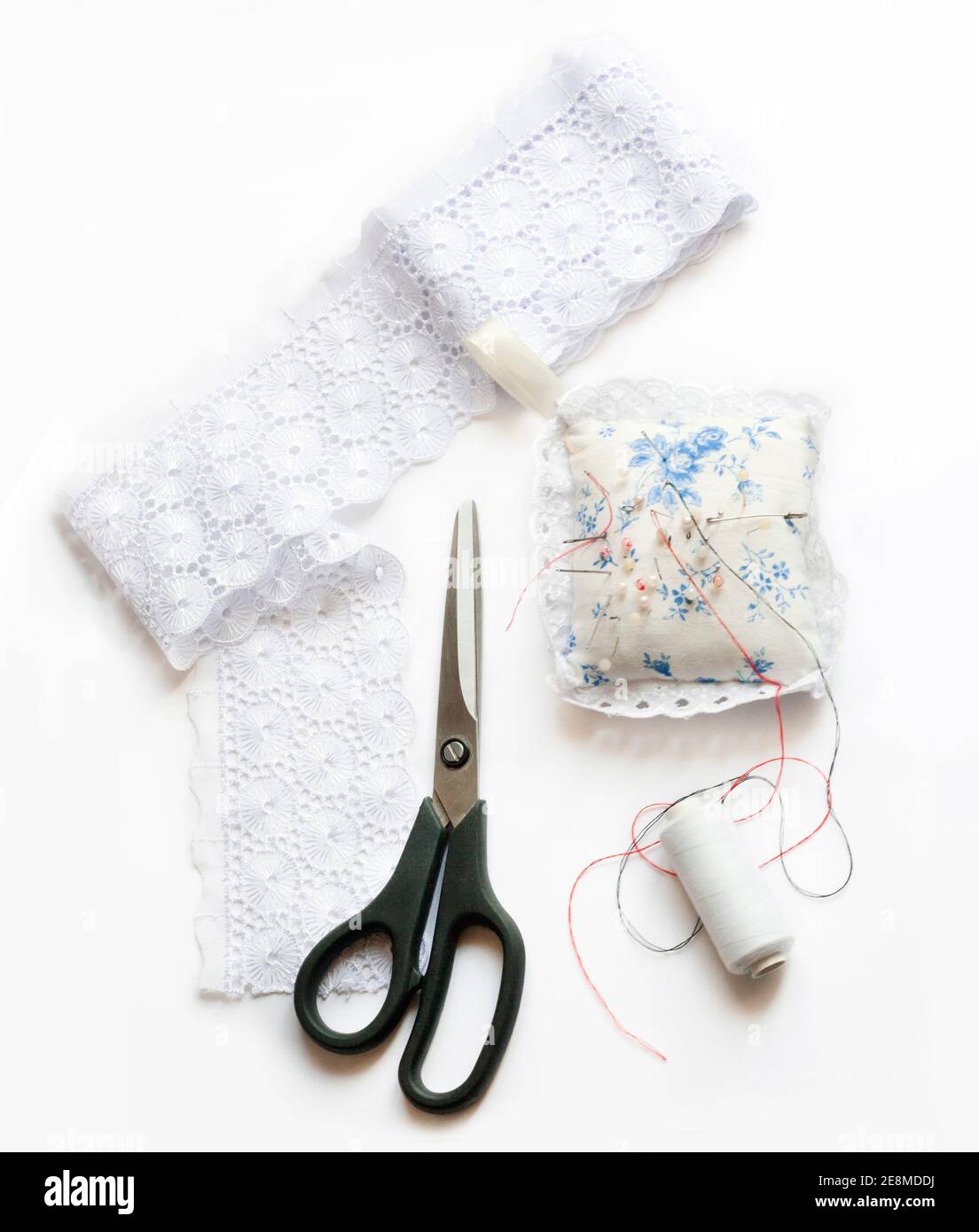 scissors, cotton lace, needle-holder with a pins and needles on white ...