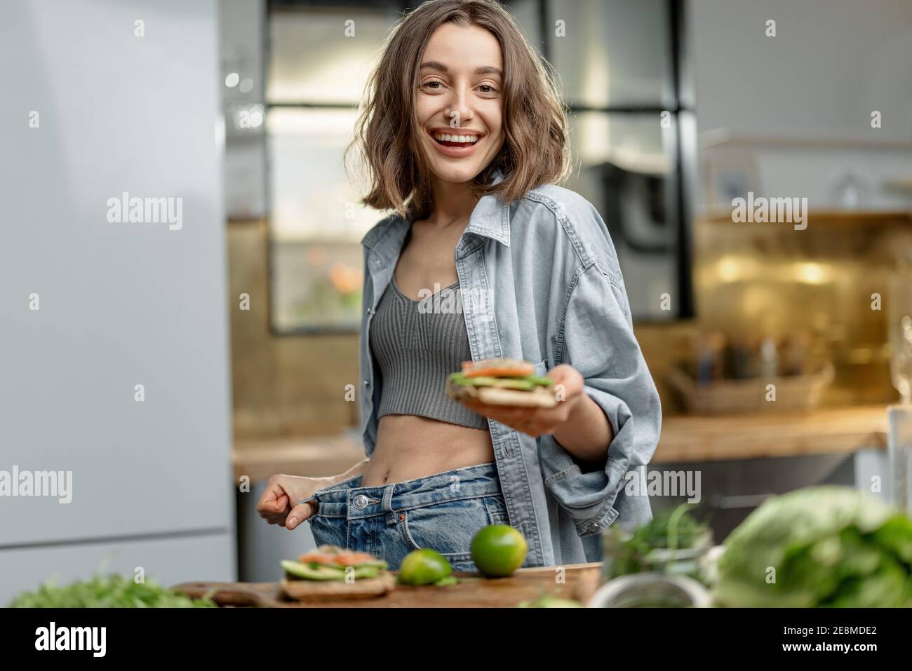 Happy slim woman showing her weight loss Stock Photo - Alamy