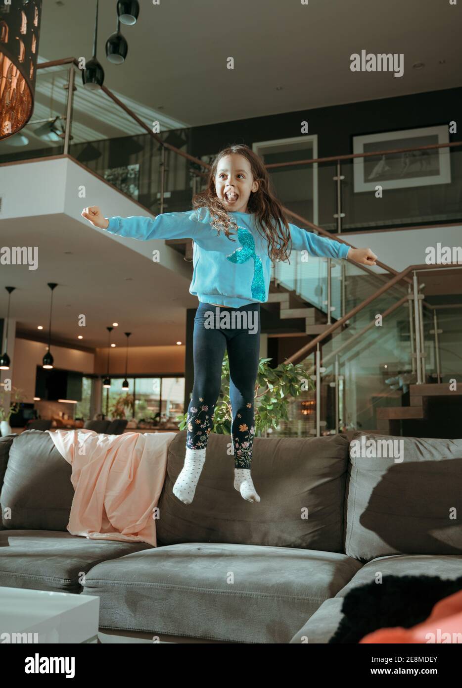 Cute, joyful girl jumping on te couch Stock Photo - Alamy