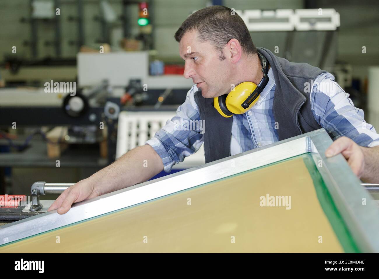 workman lifting awkward object in a factory Stock Photo - Alamy