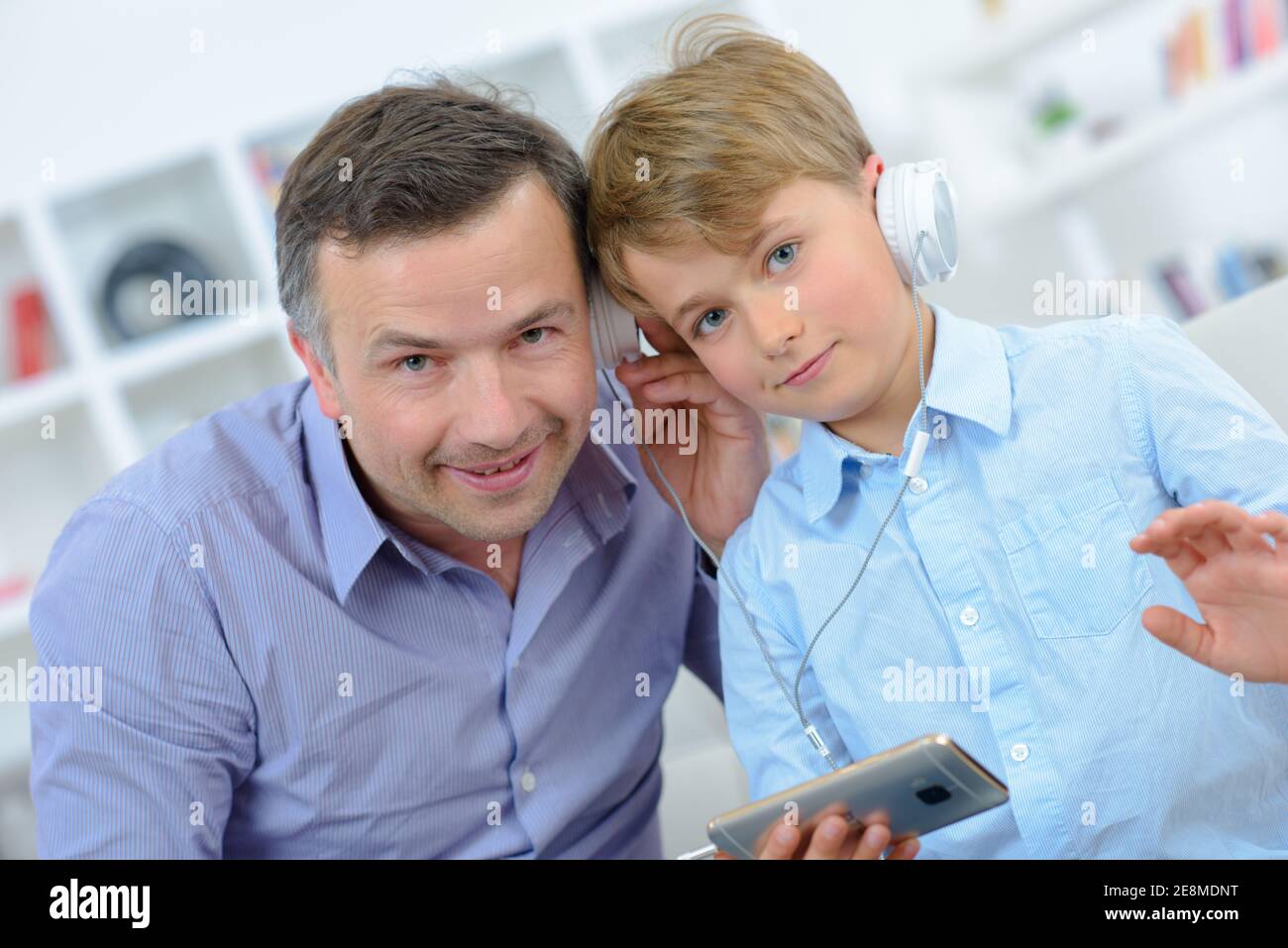 a dad is listening to childs headphones Stock Photo - Alamy