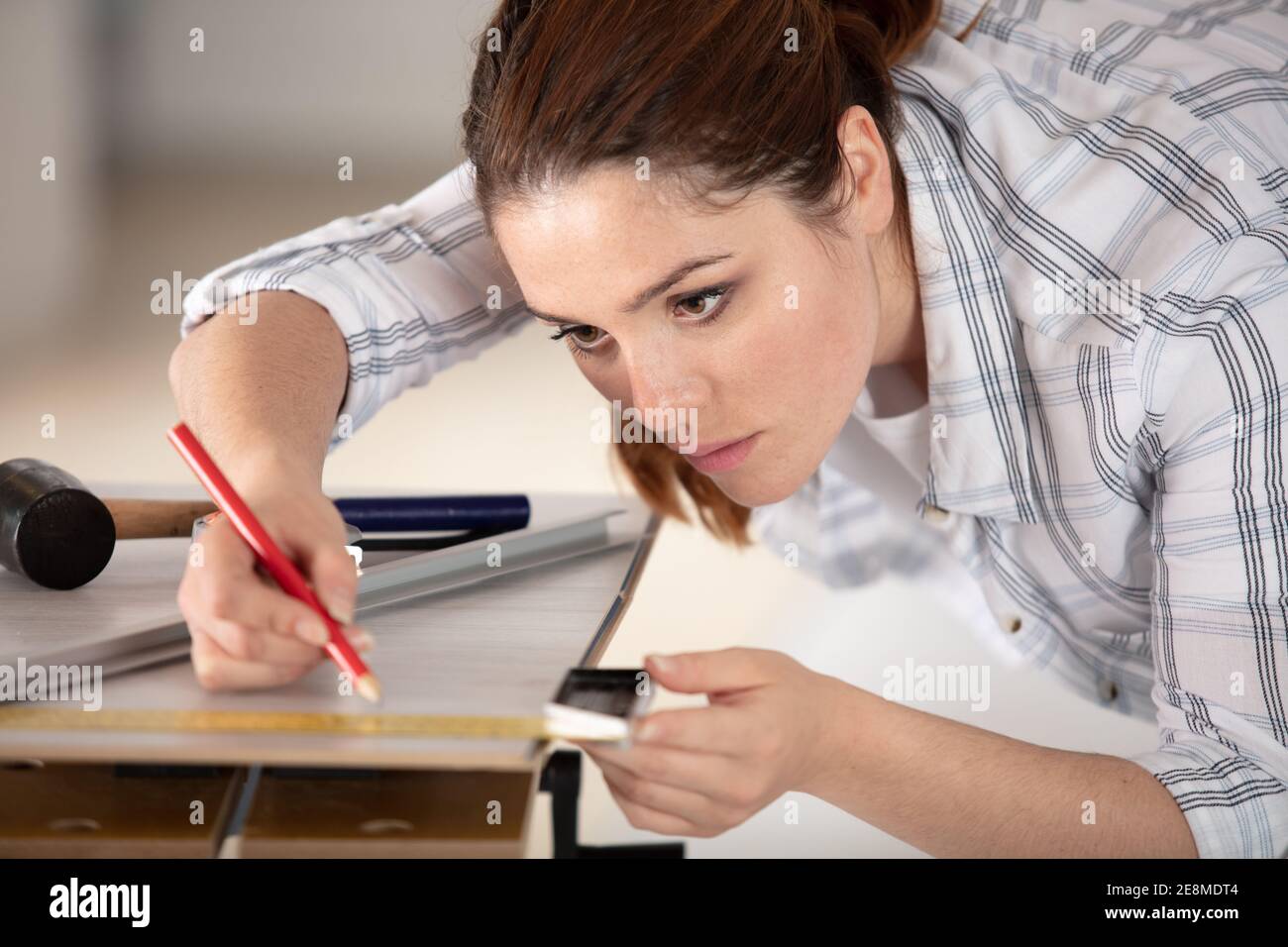 serious carpenter woman holding ruler and pencil while making wood ...