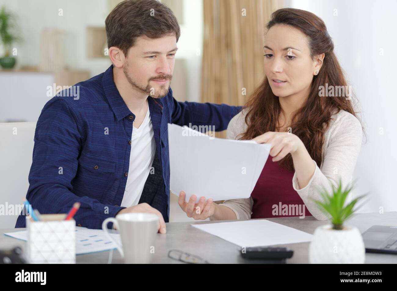 couple sat at the table looking at papers Stock Photo - Alamy