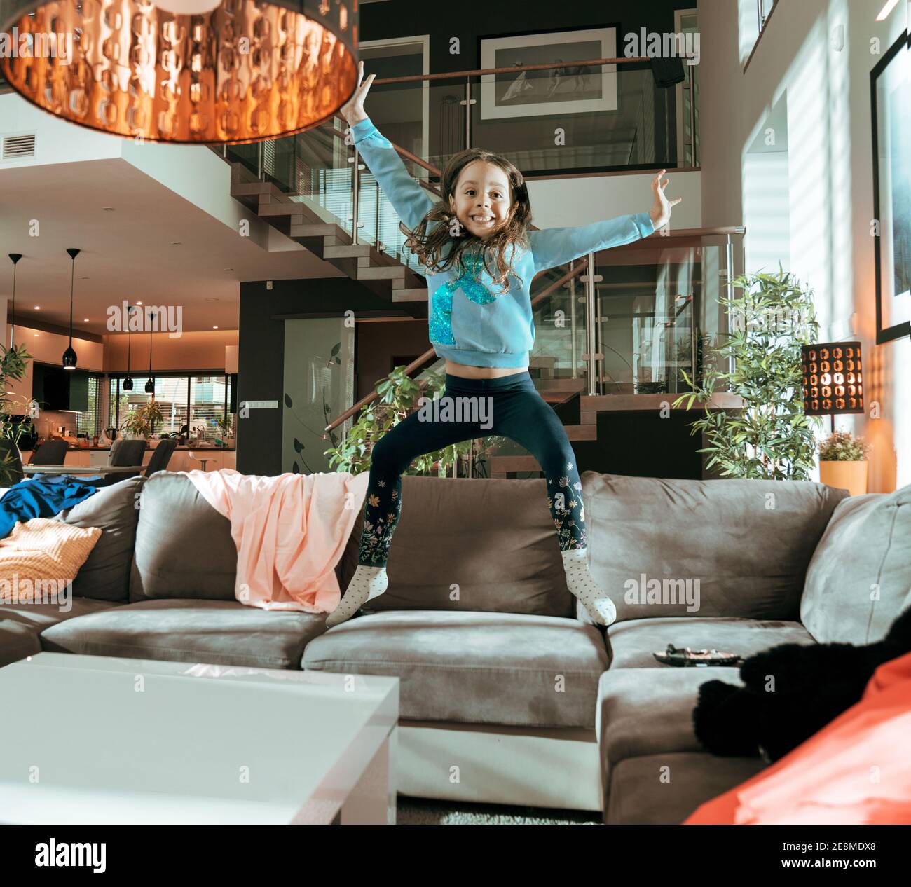 Cute, joyful girl jumping on te couch Stock Photo - Alamy
