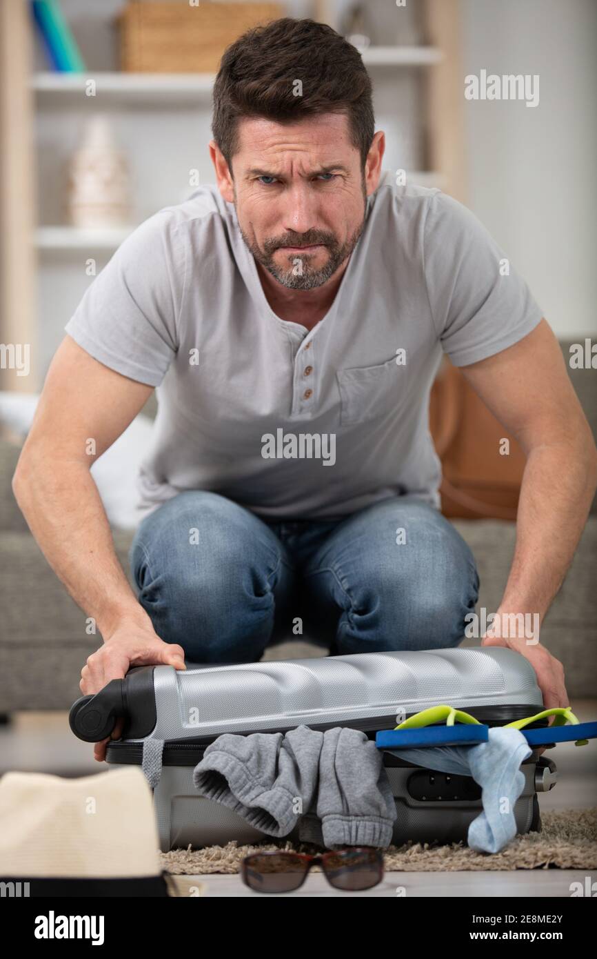 man tries to close a full suitcase Stock Photo - Alamy