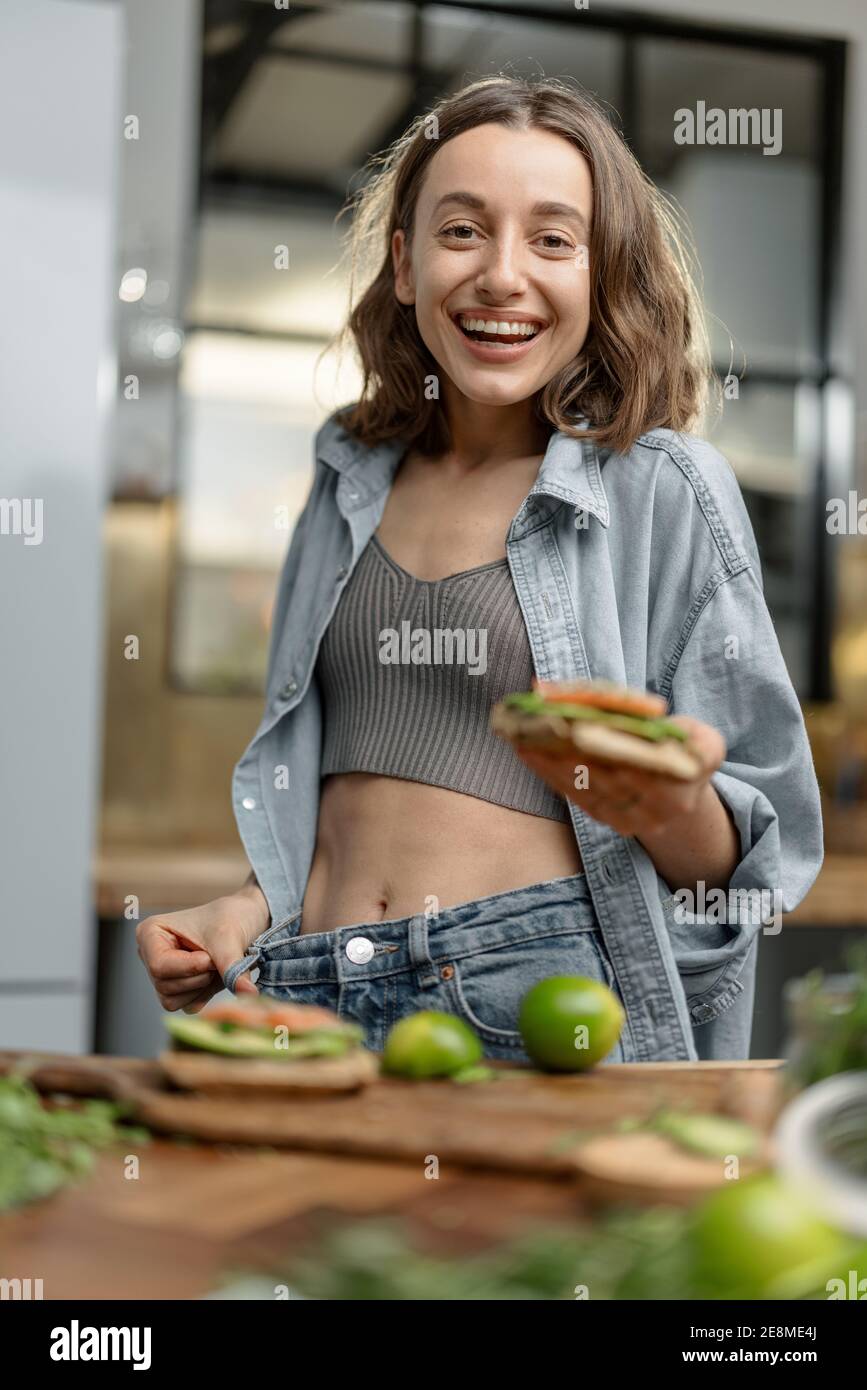 Happy slim woman showing her weight loss Stock Photo - Alamy