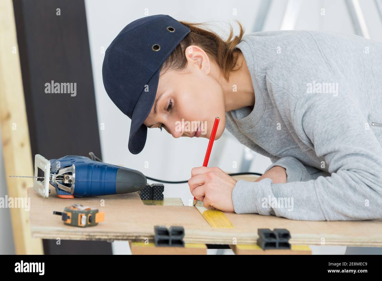 female crafter measuring wood jigsaw on workbench Stock Photo - Alamy