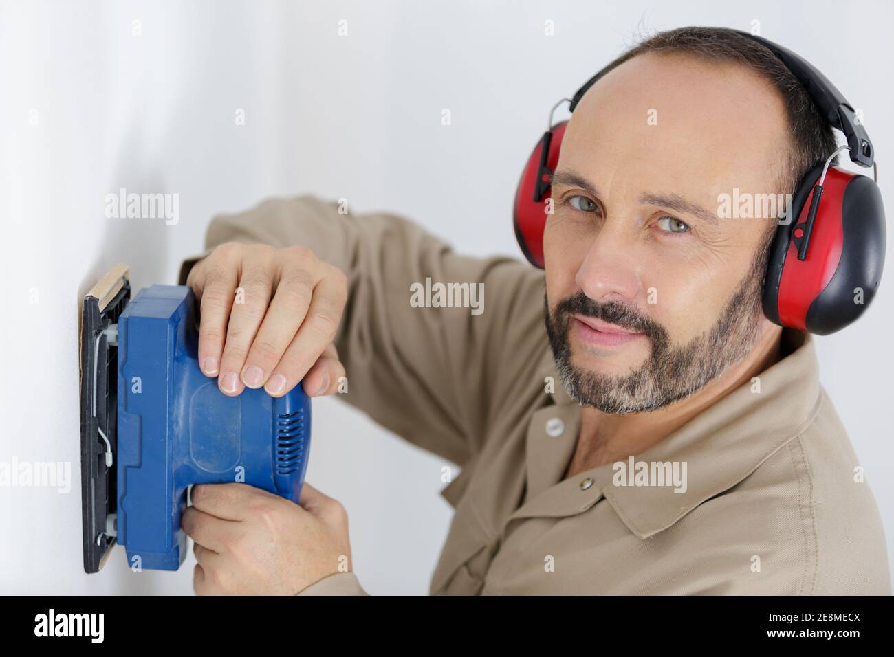 man using power sander on wall Stock Photo - Alamy
