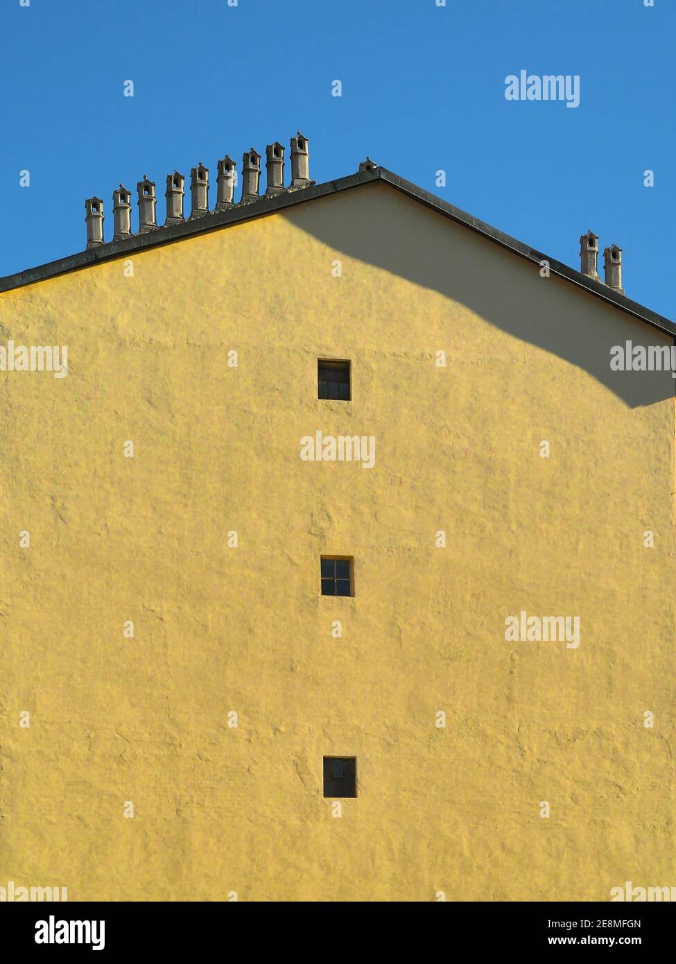 A vertical shot of three small window frames row on concrete wall ...