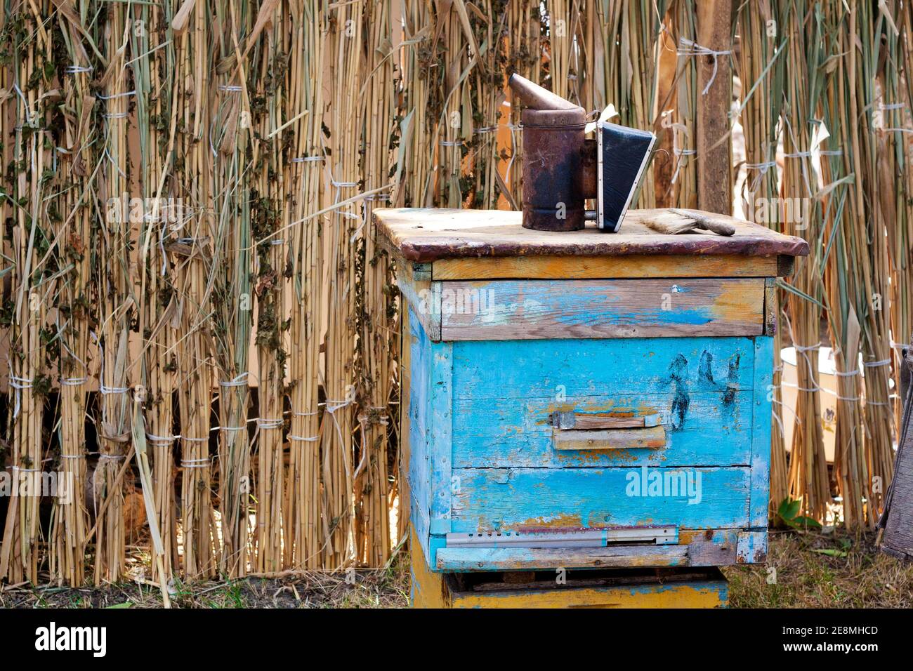 Old fashioned weathered blue wooden bee hive with bee-keeper tools in ...