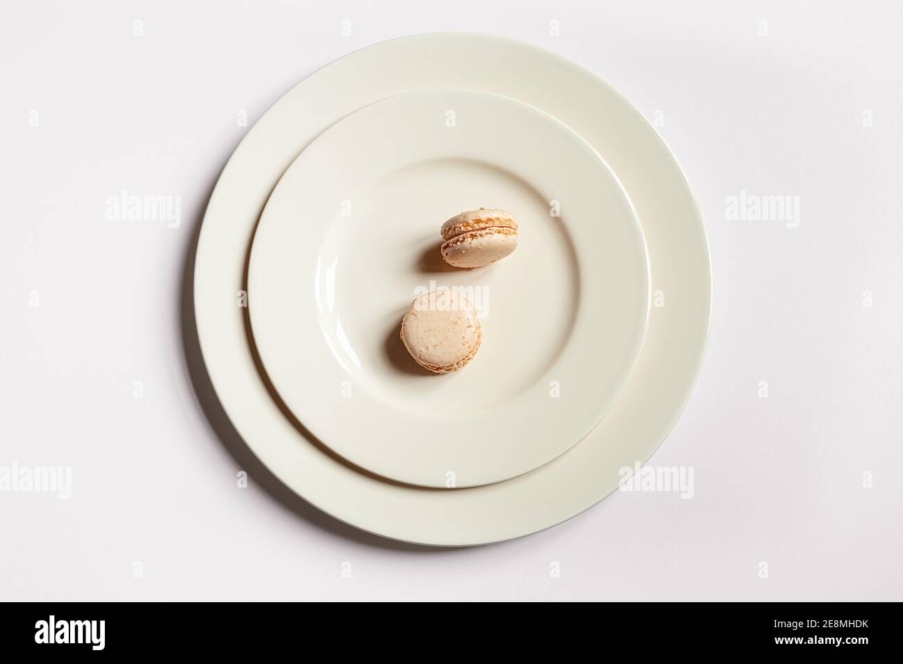 Two light macaroons in a light plate on a light background, minimalist ...