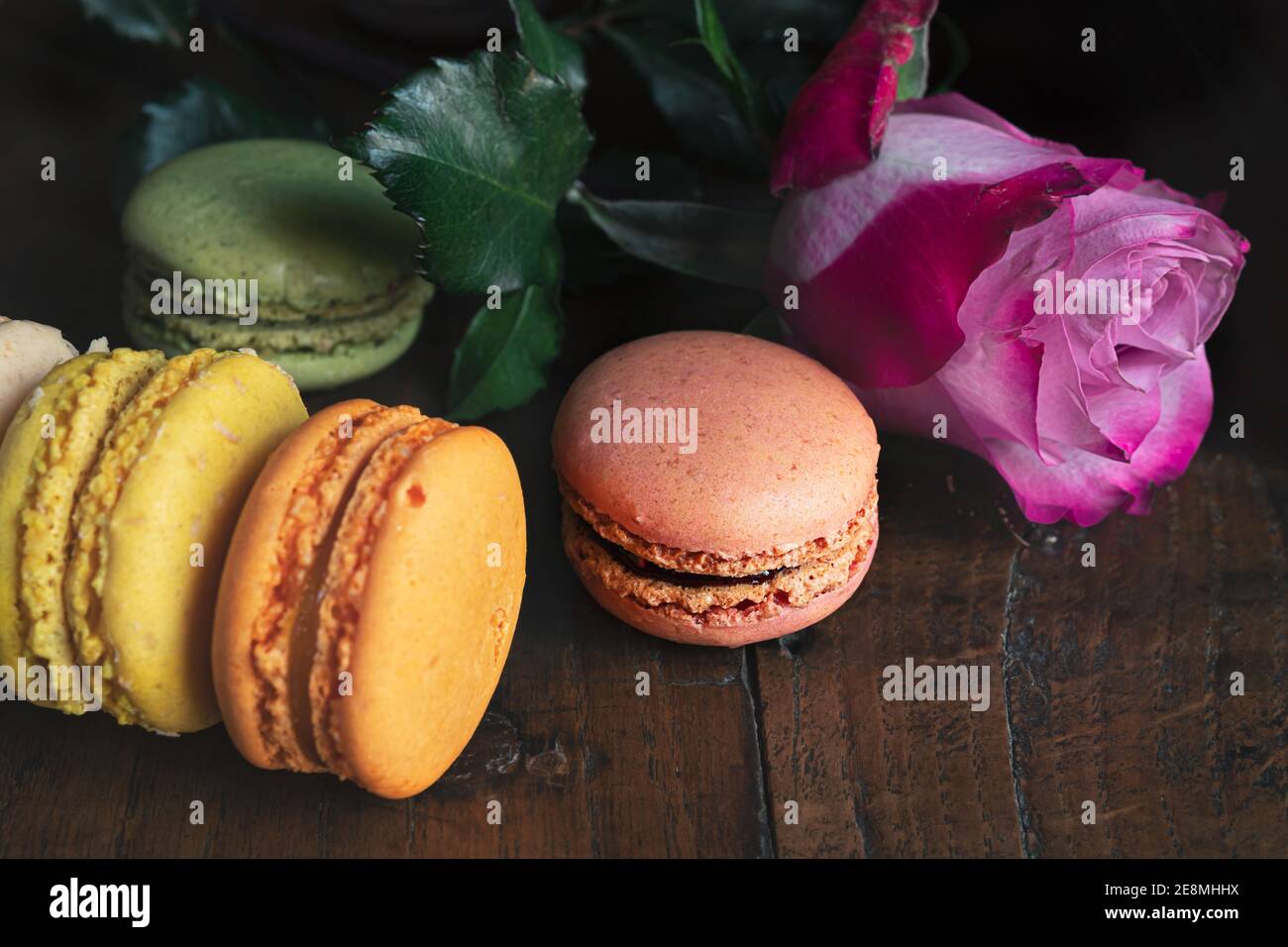 Several delicious classic macarons and a rose on an old vintage dark ...