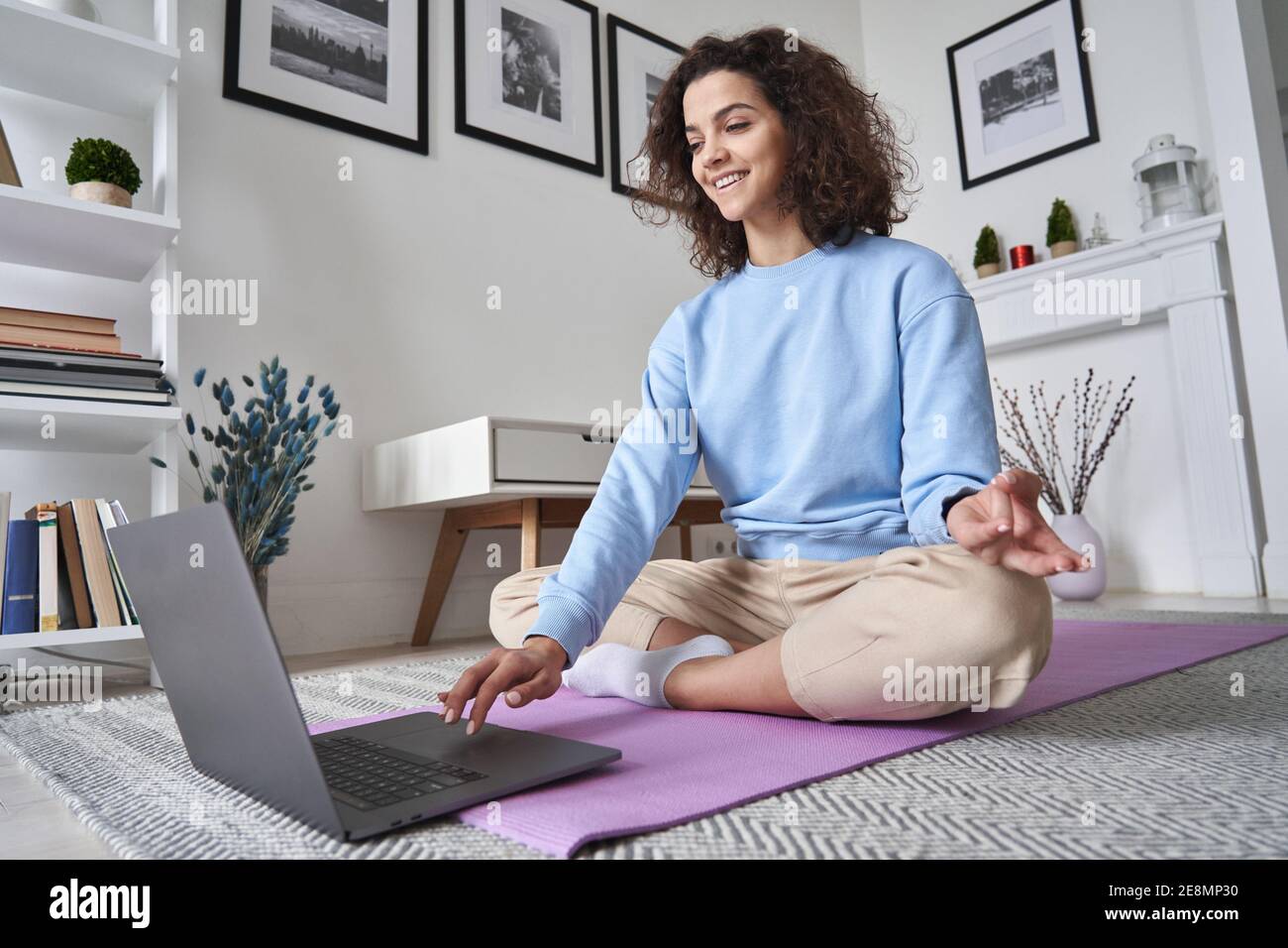 Happy fit young woman using laptop watching online yoga lesson at home ...