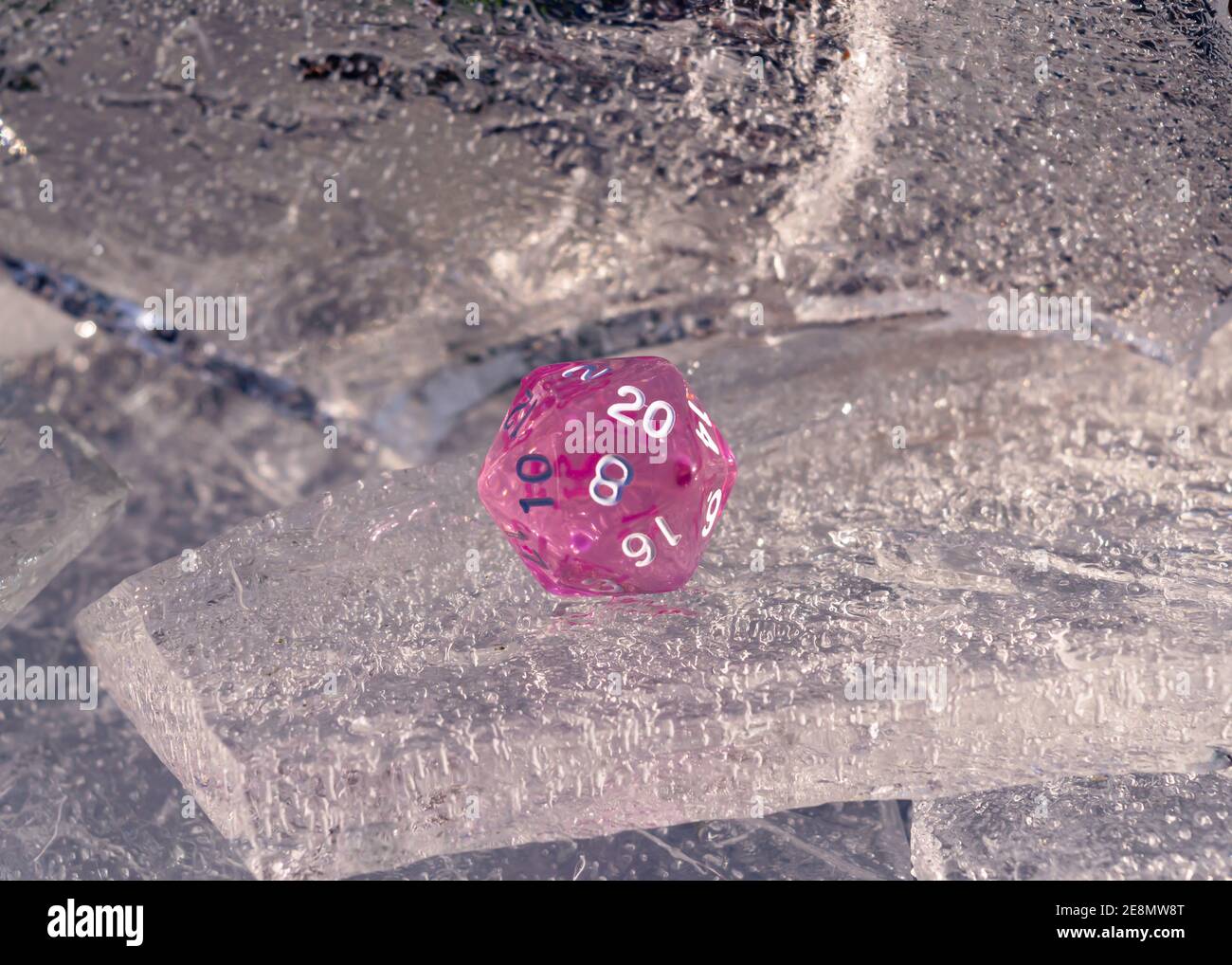 Image of one pink 20 sided role playing die on a sheet of ice in the ...