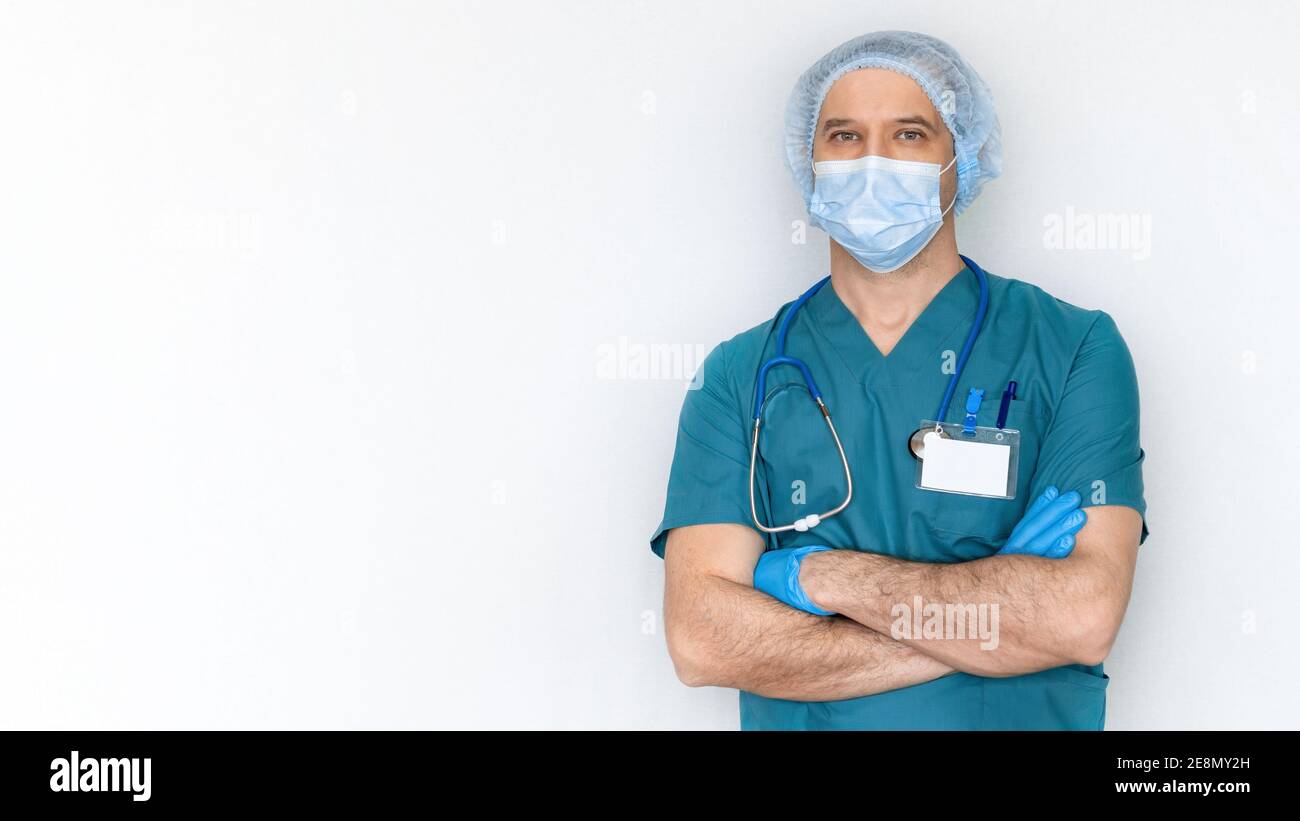 Male surgeon in a blue suit, mask and gloves close up isolated on a ...