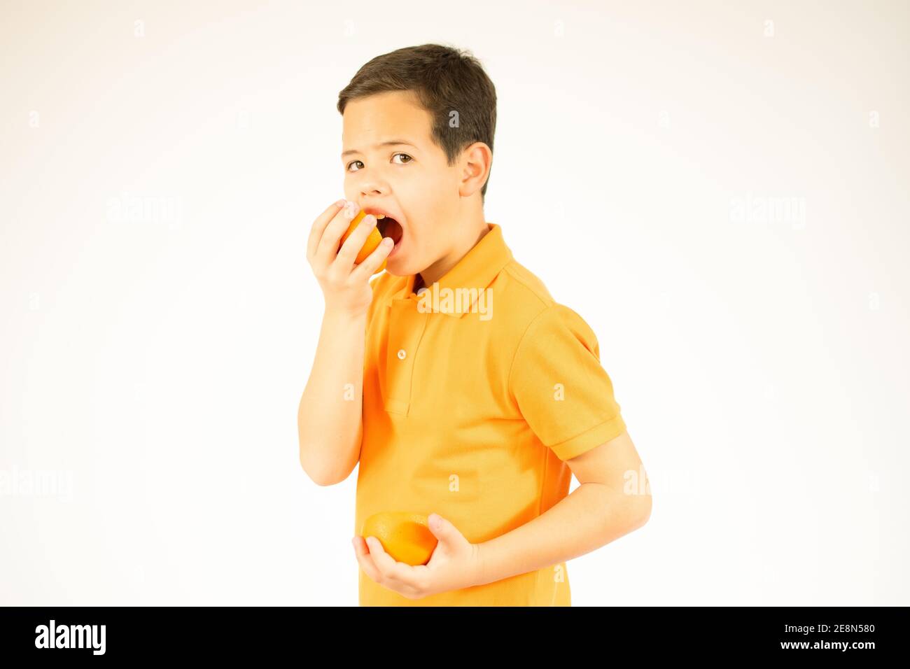 Young boy eating a orange isolated on white Stock Photo - Alamy