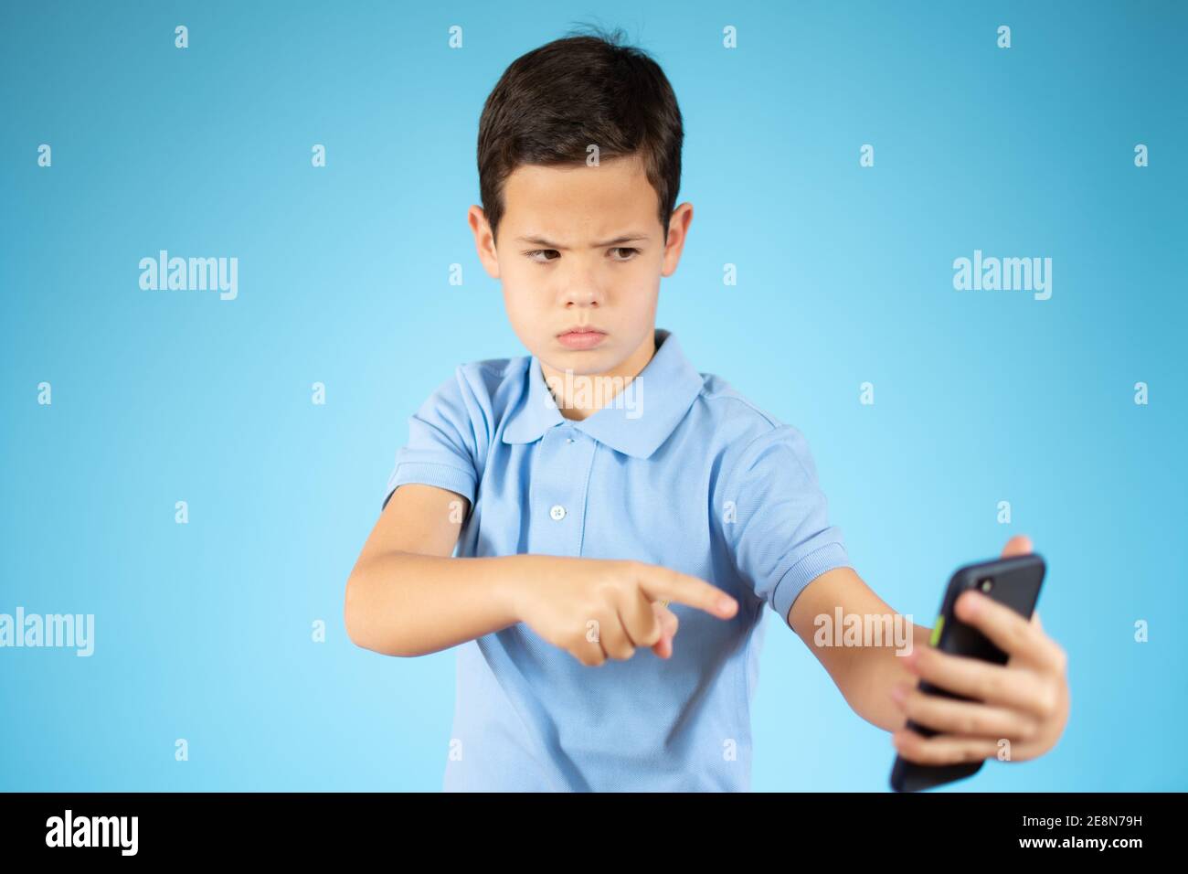 Cute ginger kid with mobile phone on blue studio background, using ...