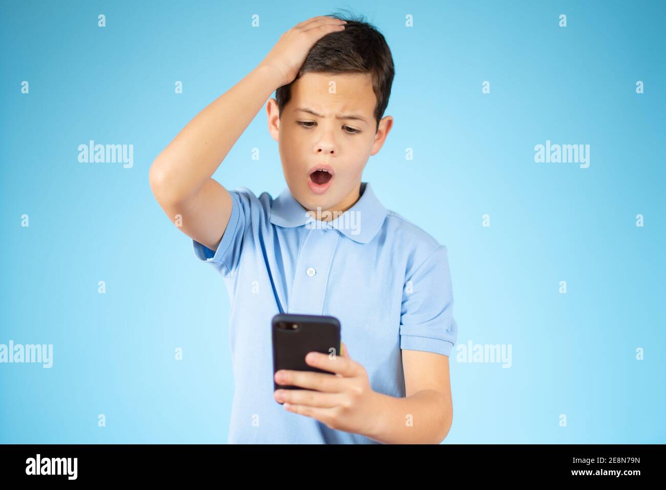 Cute ginger kid with mobile phone on blue studio background, using ...