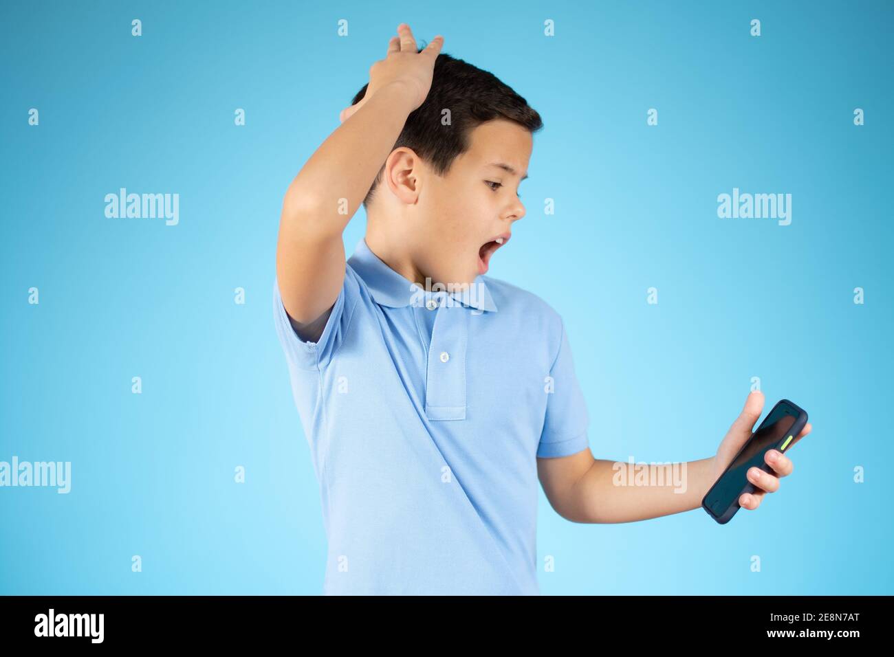 Cute ginger kid with mobile phone on blue studio background, using ...
