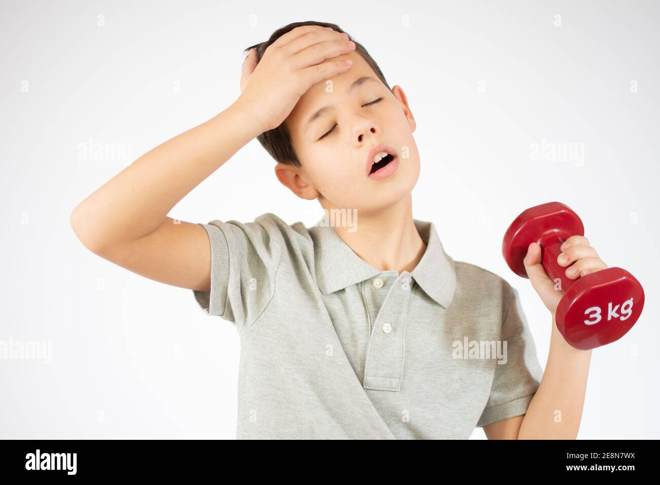 Beautiful caucasian boy tired with dumbbells over white background ...