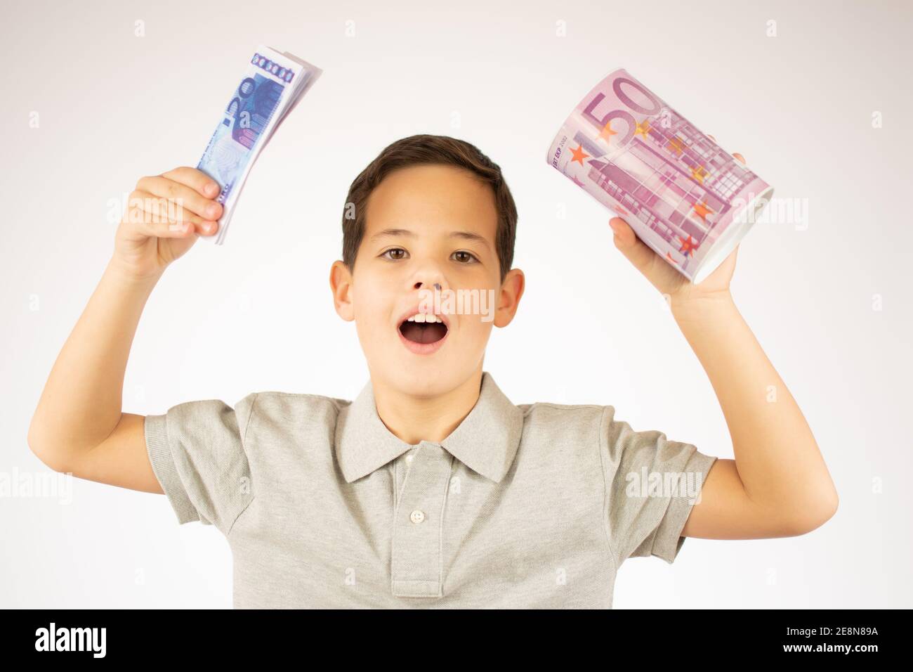 Portrait of a smiling young boy holding money banknotes and celebrating ...