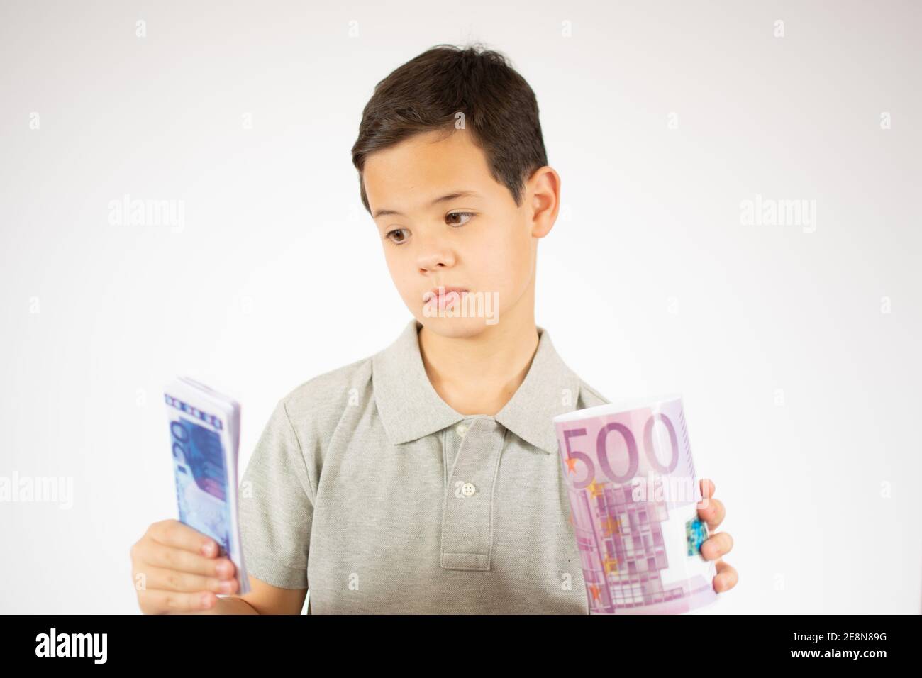 Portrait of a smiling young boy holding money banknotes and celebrating ...