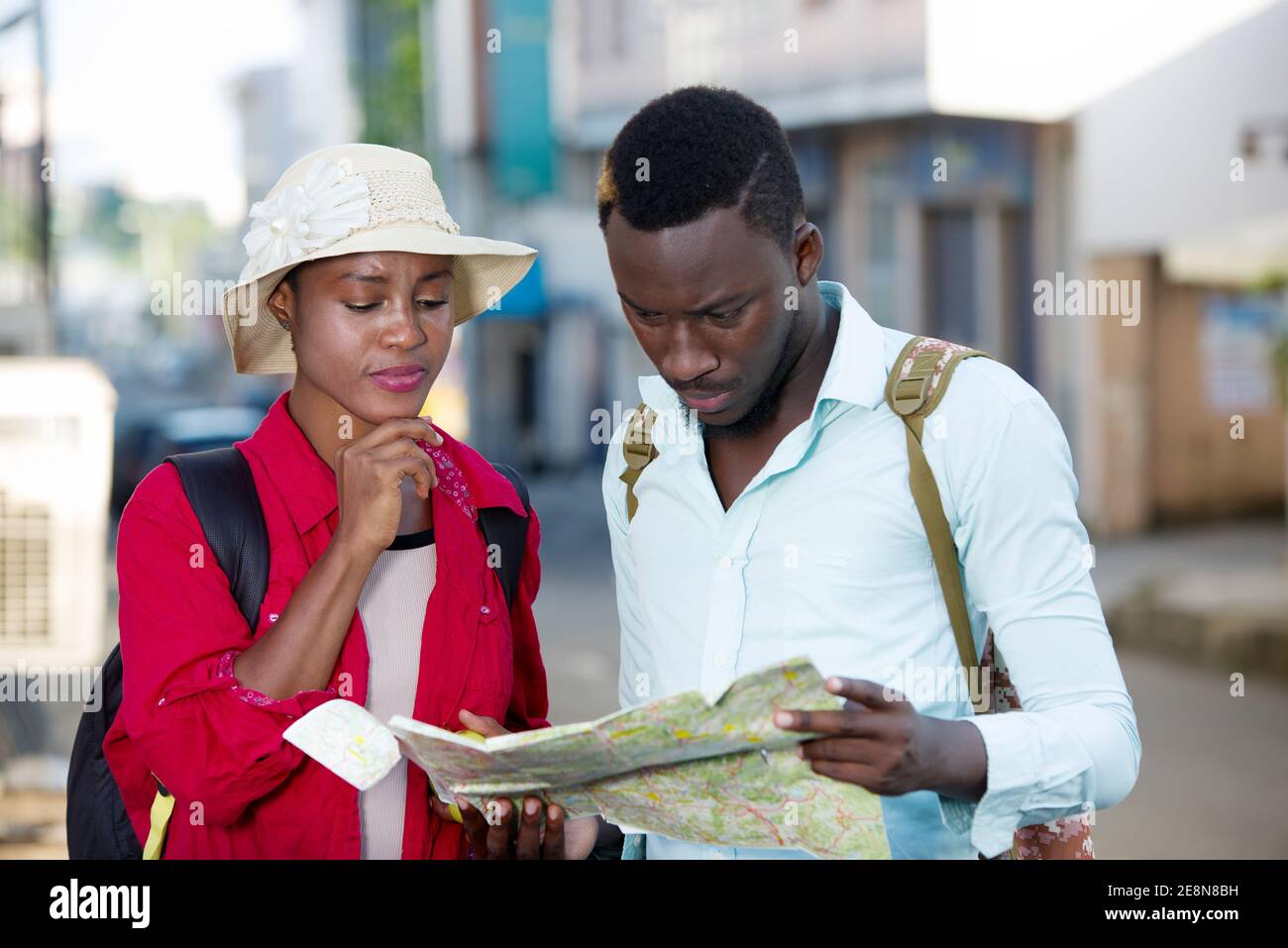 Young tourists standing outdoors looking at map Stock Photo - Alamy