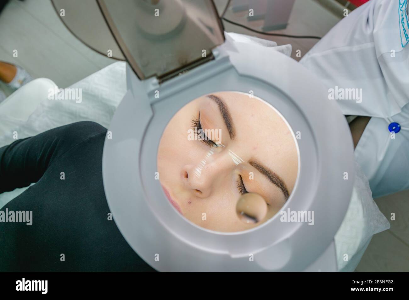 Woman eye through magnifying glass in spa salon. Face mask. Skin ...