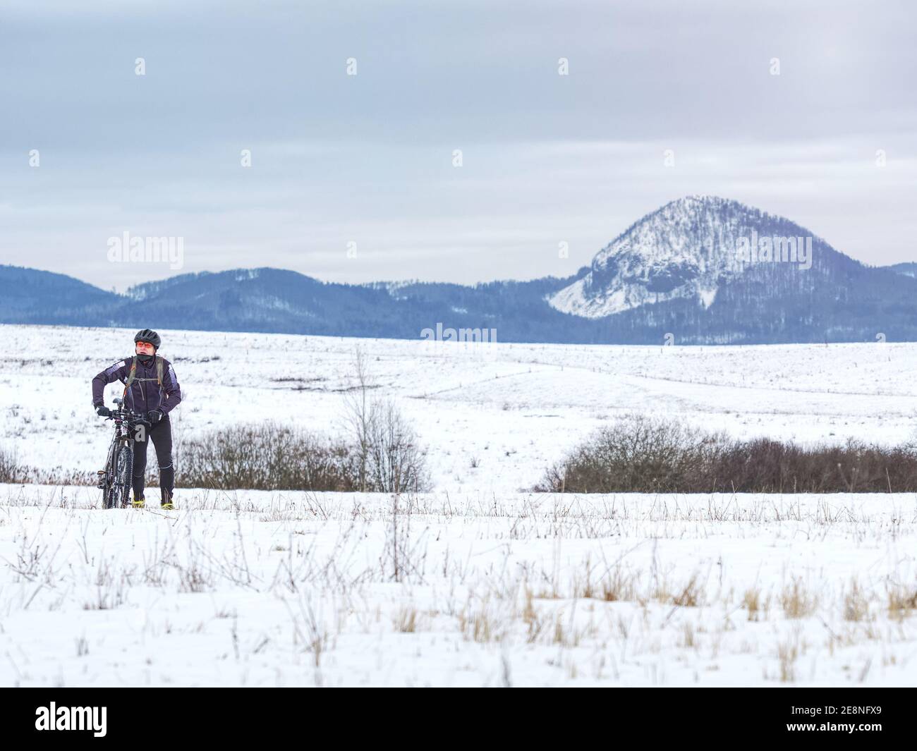 Man biker pushing mountain bike in snowdrift. Freeze sunny winter ...