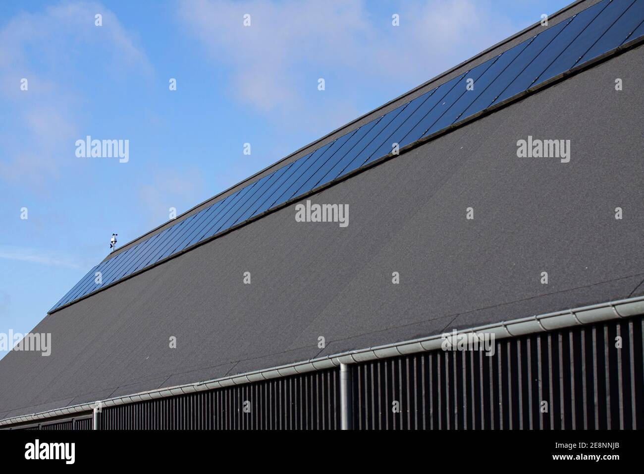 Black solar panels on roof of a modern wooden commercial building with ...