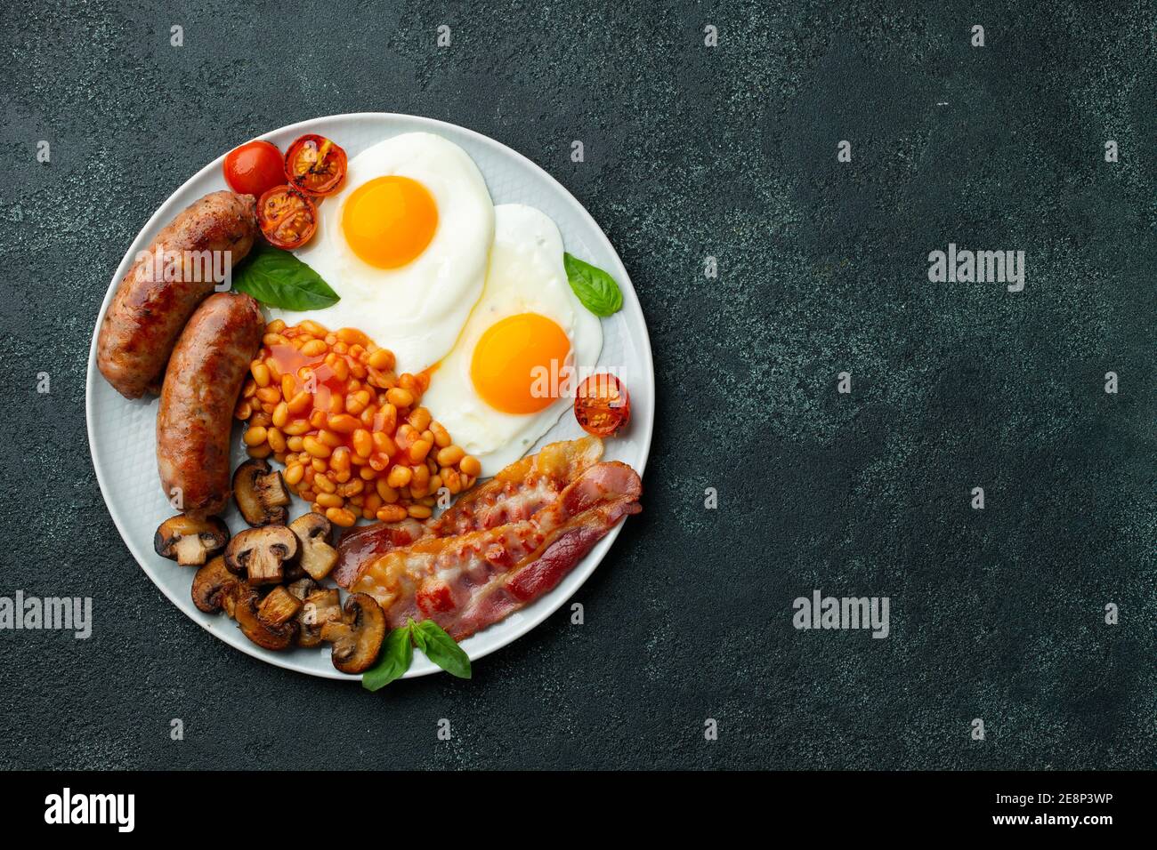 Full English breakfast on a plate with fried eggs, sausages, bacon ...