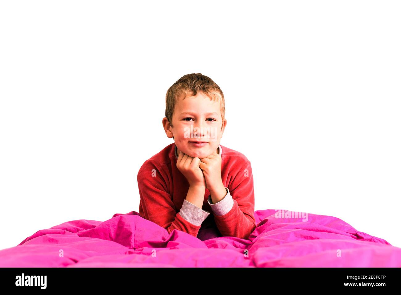 Handsome little boy wakes up and poses sitting on his bed covered by a ...
