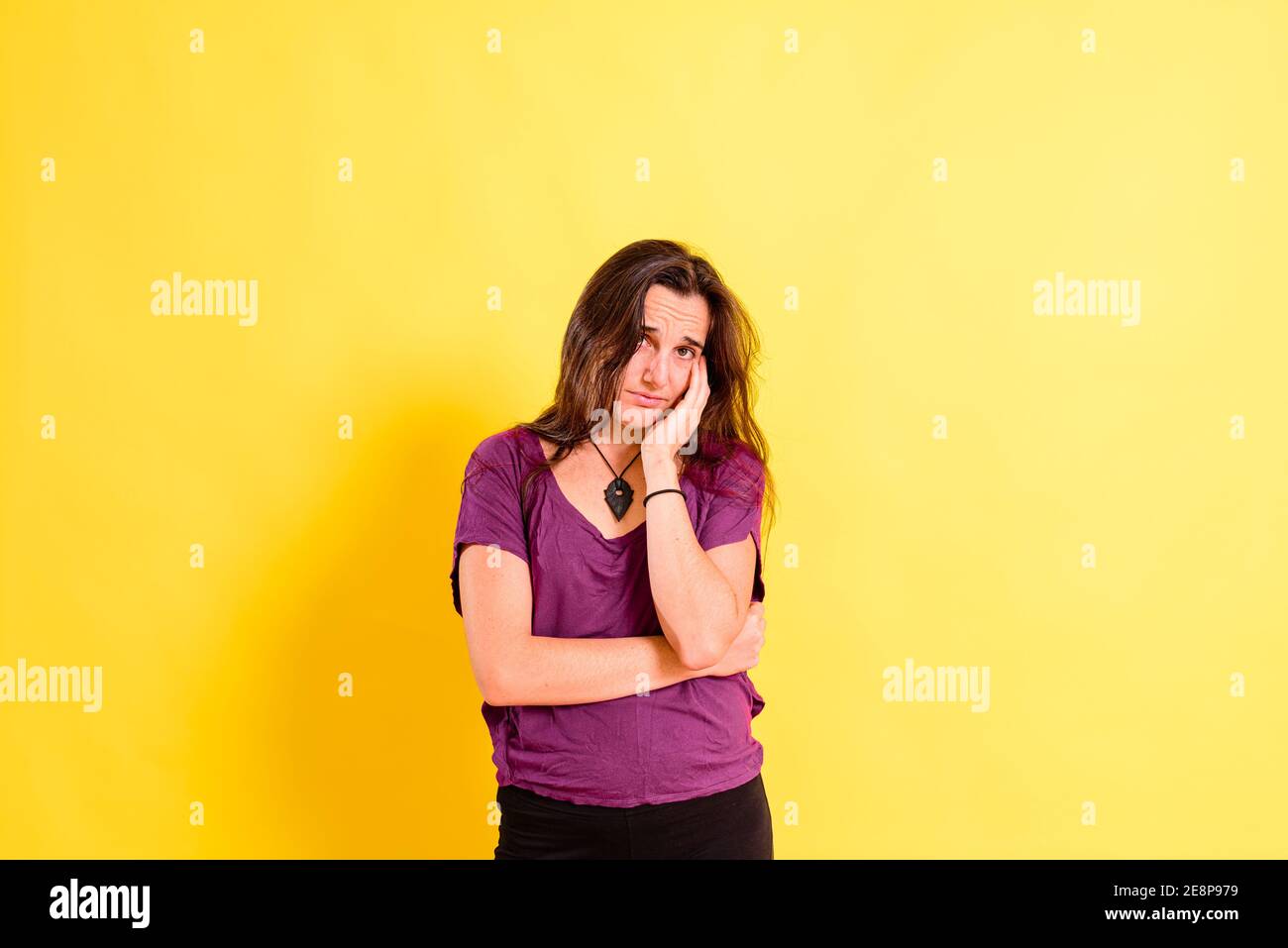 Young woman with anguished and uneasy expression, isolated on yellow ...