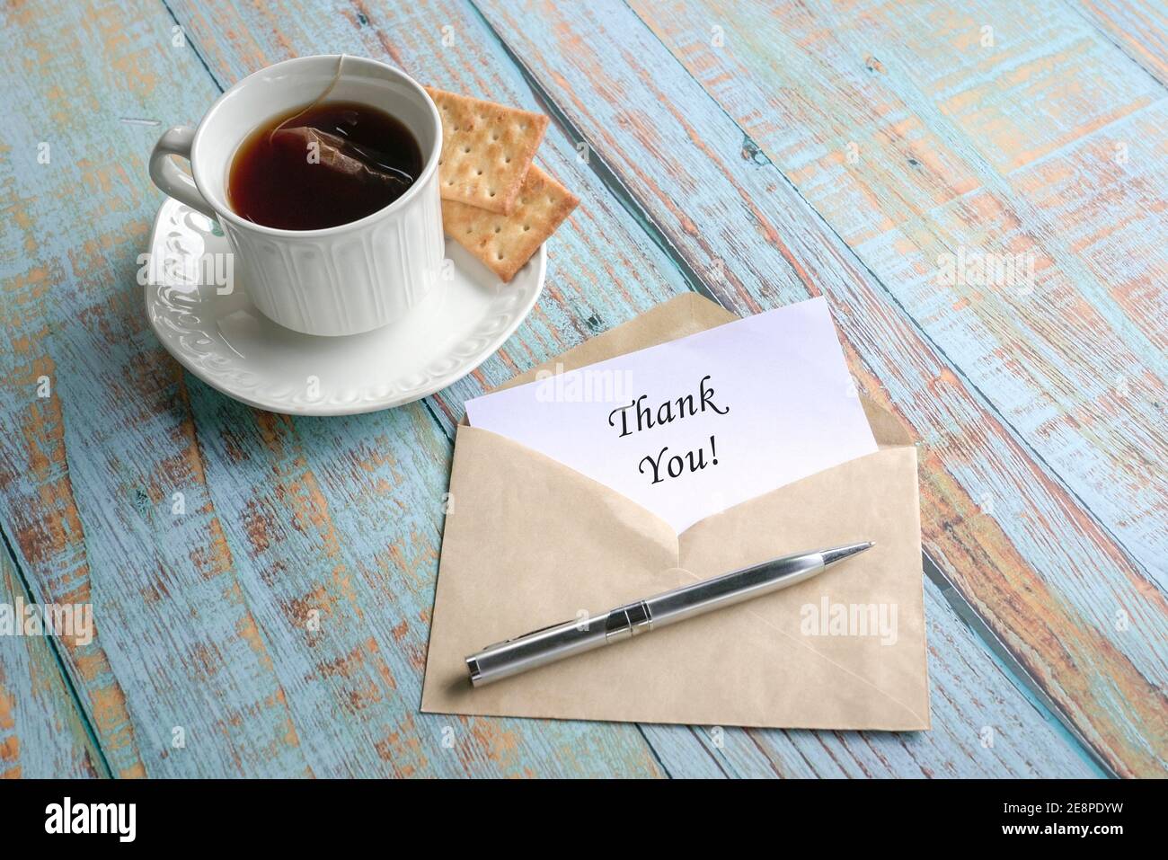 Thank you card inside brown envelope with pen, next to cup of tea and ...