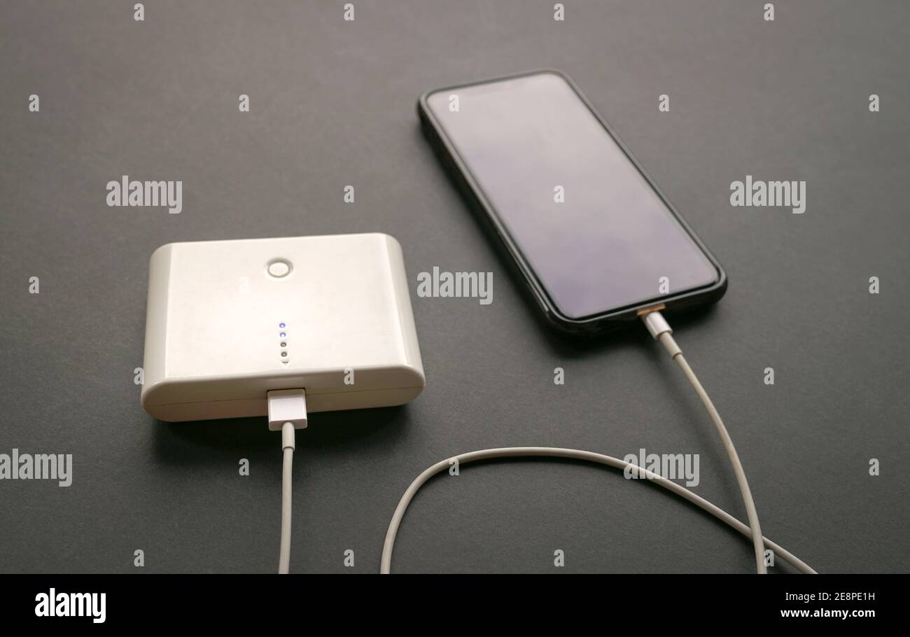 Cellphone getting charged from power bank. Isolated. On black ...