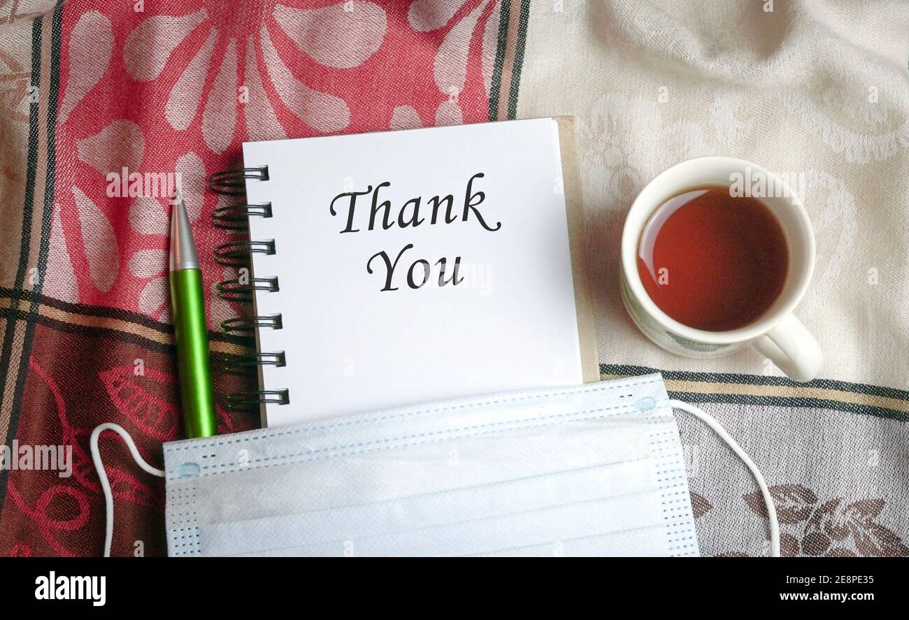 Thank you, words on notepad, with cup of coffee, pen and face mask. Top ...