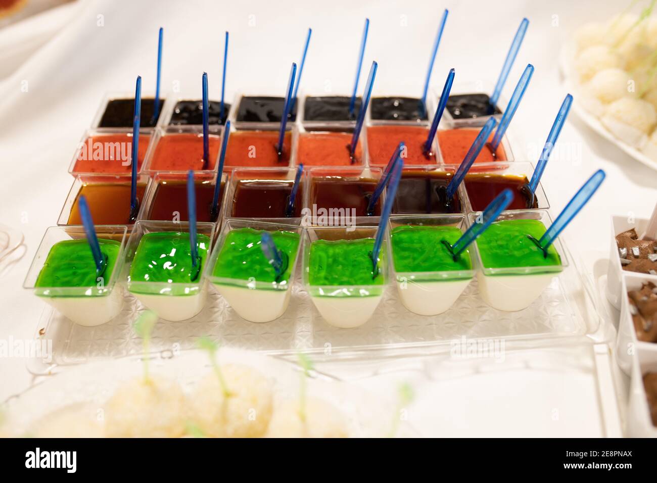 the rows of colorful edible jelly in small containers with blue plastic ...