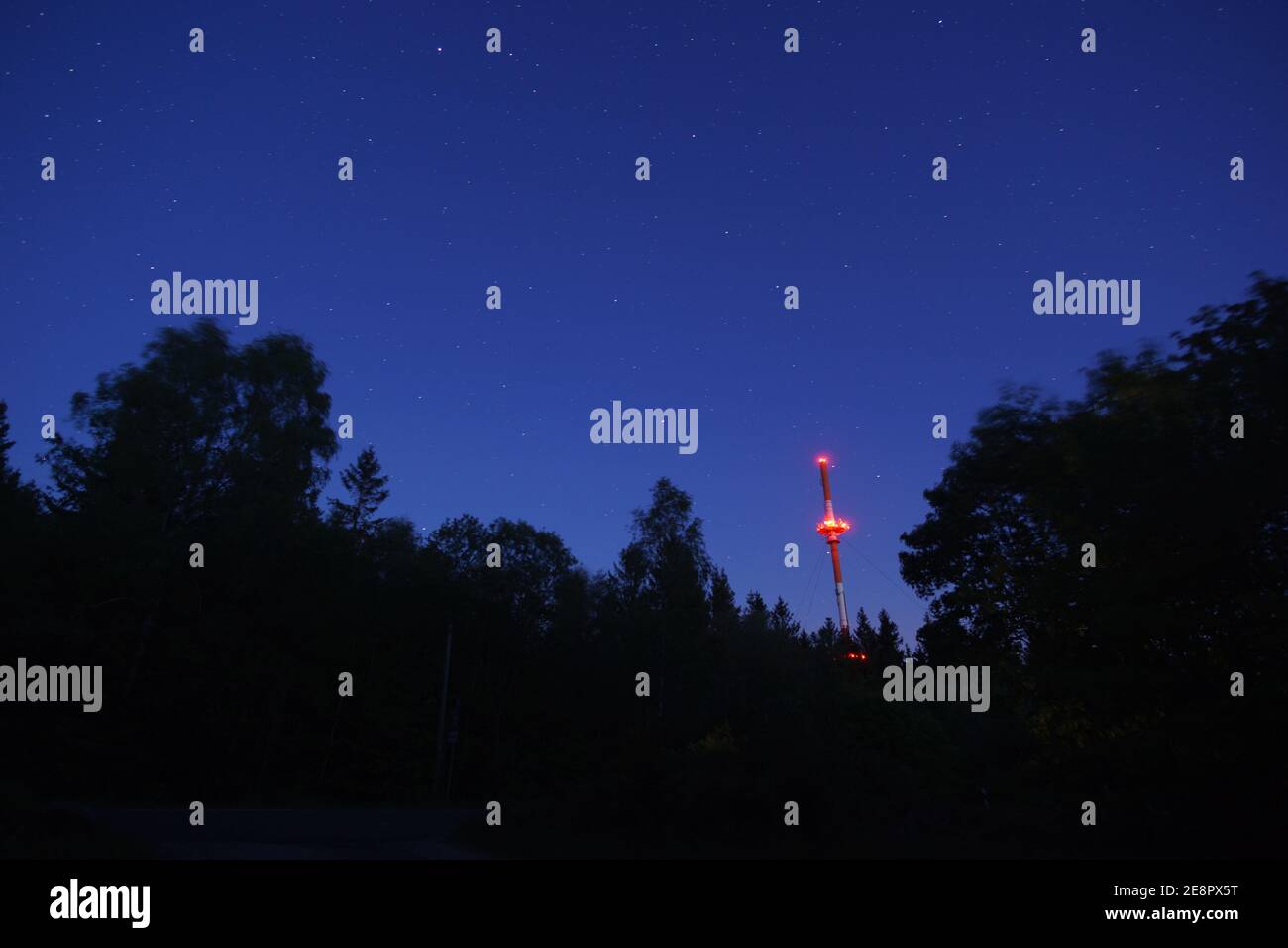 Radio tower at night with stars and silhouette of trees in the forest ...