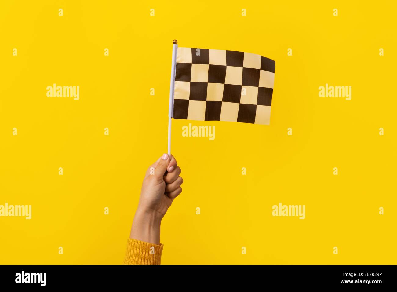 checkered flag in hand over yellow background Stock Photo - Alamy